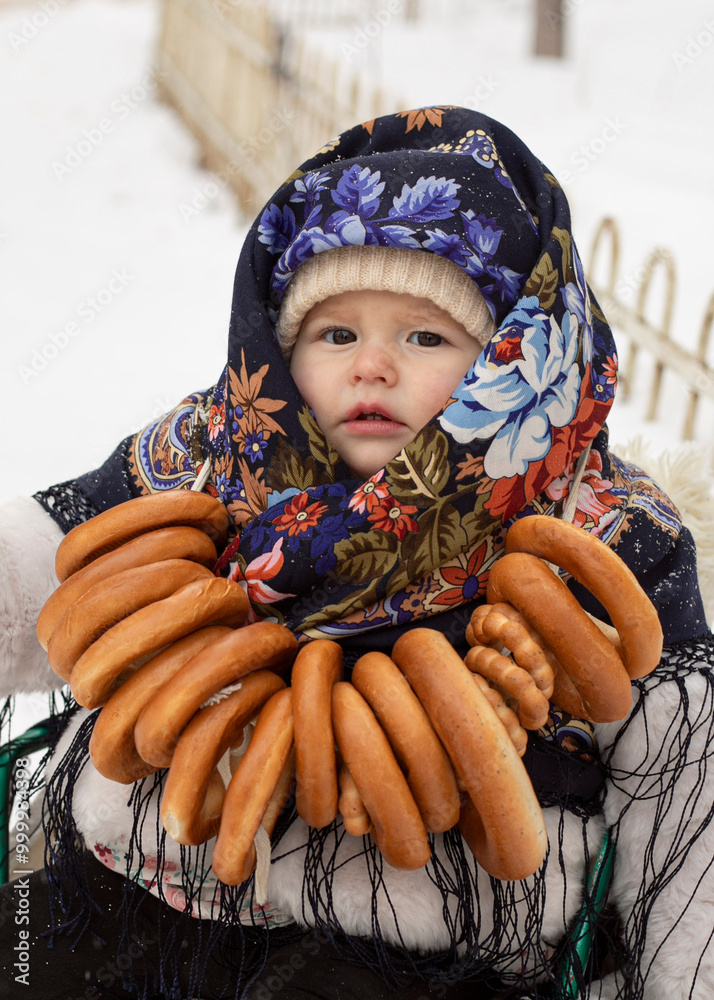 Pretty baby girl sits on a sled in winter, wrapped in a russian scarf ...