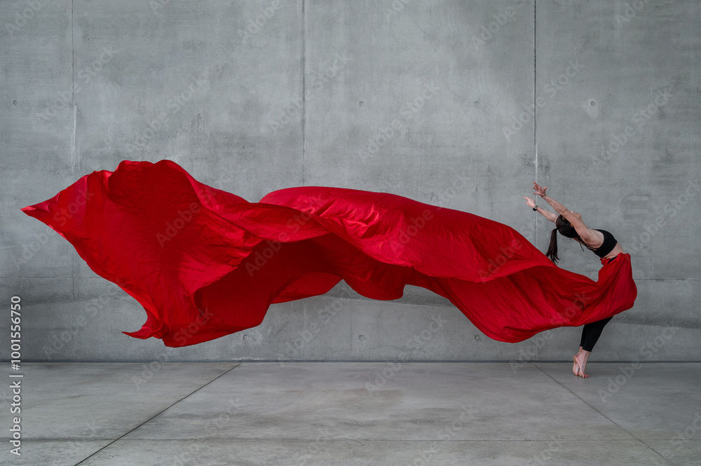 Danseuse classique qui joue avec un grand voile de couleur rouge devant ...