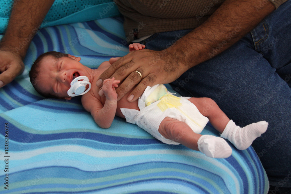 Foto Premature baby in diapers and with a pacifier crying next to his ...