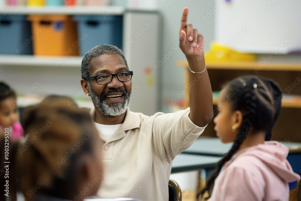 African American teacher points at girl raising hand in classroom ...