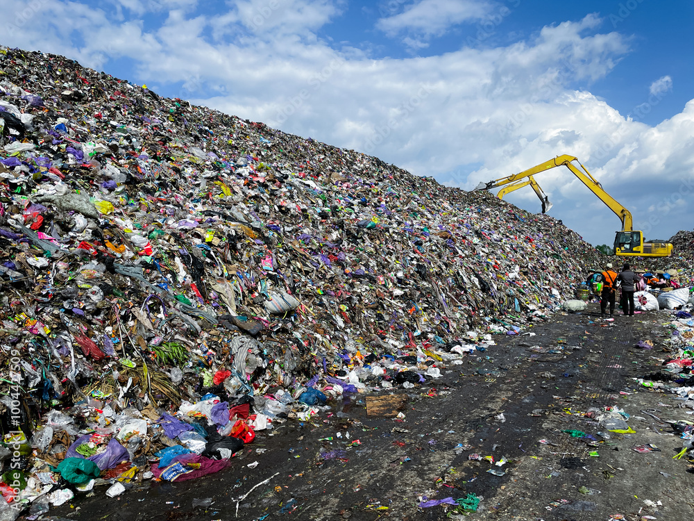 Heavy excavator vehicles work amidst piles of rubbish at landfills ...