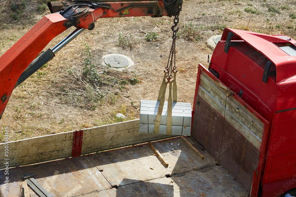 loader crane unloads concrete garden barriers from the truck bed ...
