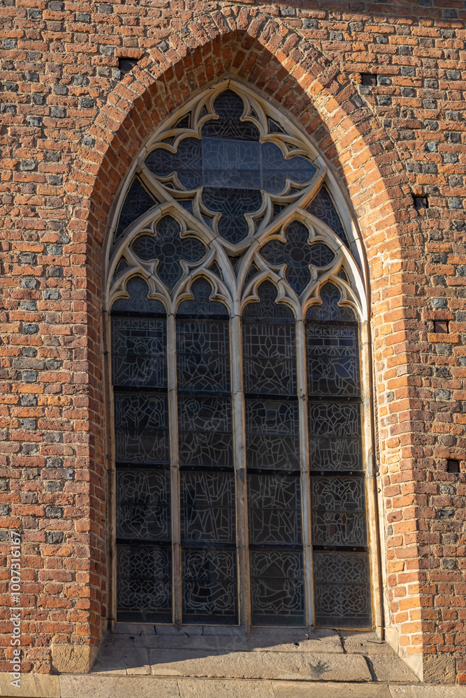 Gothic-style arched window with stained glass on a brick church wall in ...