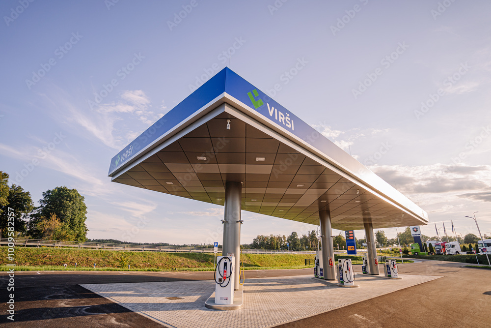 A modern gas station canopy with fuel pumps beneath a clear sky, with ...