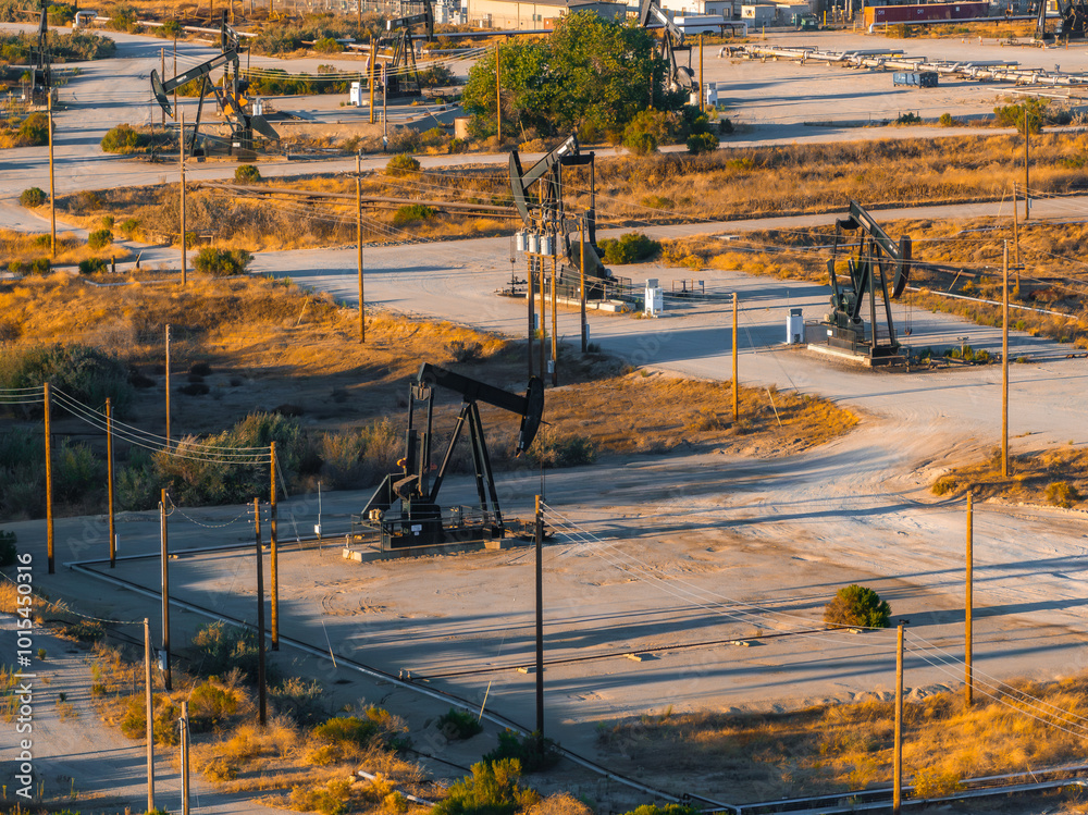 Oil rigs are scattered across an arid desert landscape in California ...