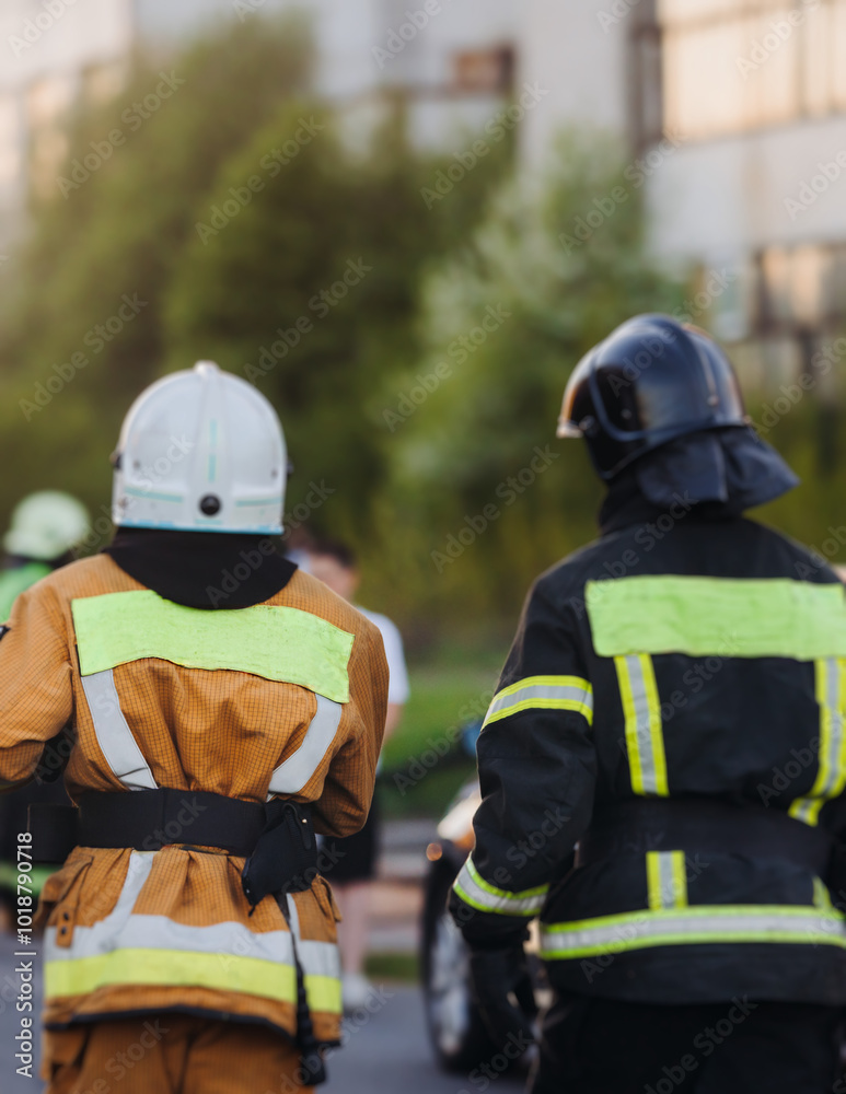 Group of fire men in uniform during fire fighting operation in the city ...