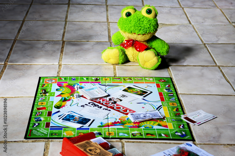 Monopoly game board on a white tile floor, on top of the board are some ...