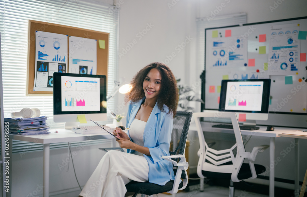 Young professional is working in a bright office, surrounded by charts ...