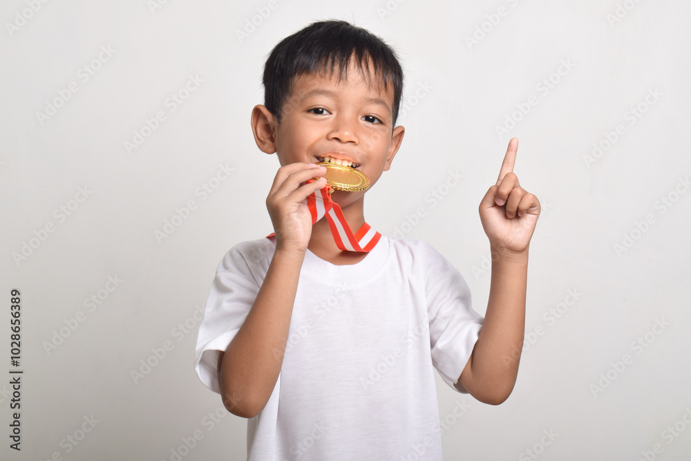 Asian boy biting the gold medal and showing a thumbs up isolated on a ...