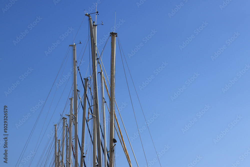 Masts of small yachts against the blue sky. Many yacht masts against ...