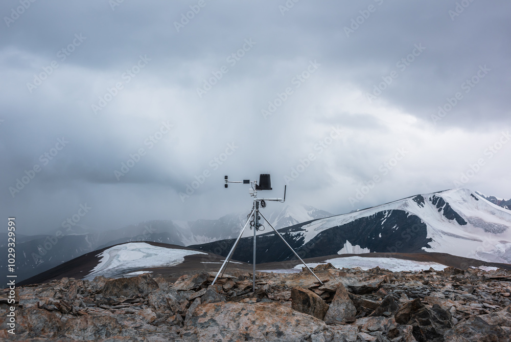Automatic meteorological station on stone hill with view to large snow ...