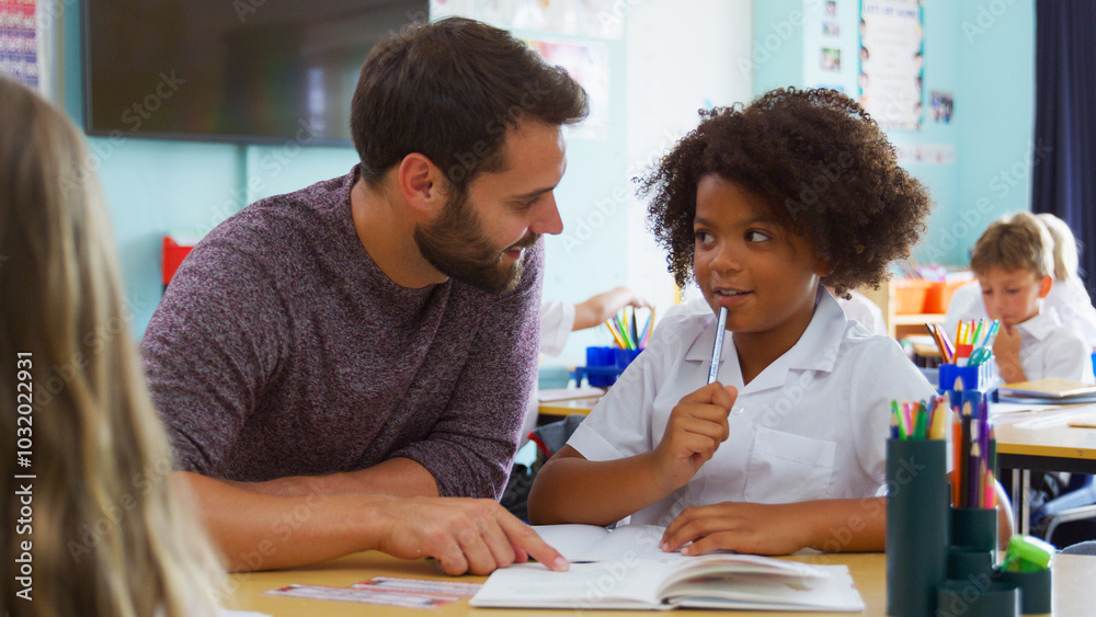 Male Elementary School Teacher Giving Female Pupil Wearing Uniform One ...