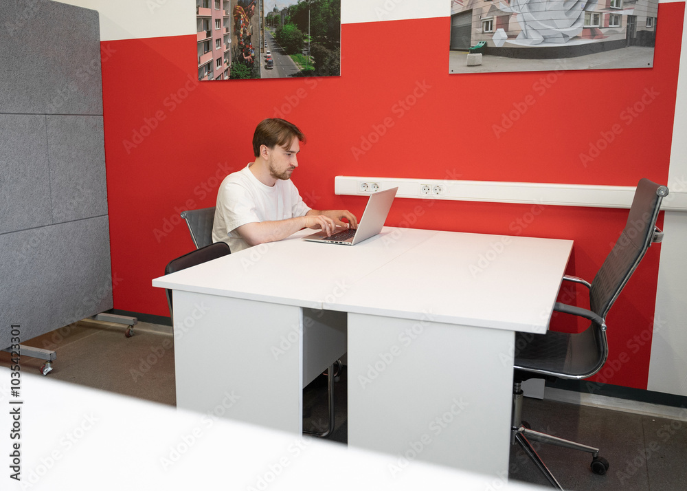 An IT specialist is deeply engaged in programming at a sleek coworking ...