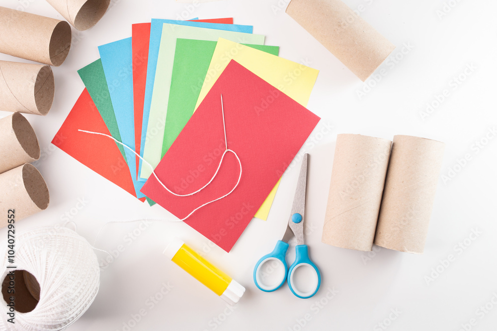 colored paper sheets, empty cardboard tubes, blue handled scissors ...