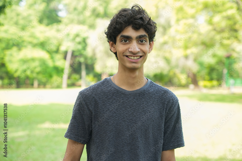 portrait of happy young indian gen Z boy standing at summer park ...