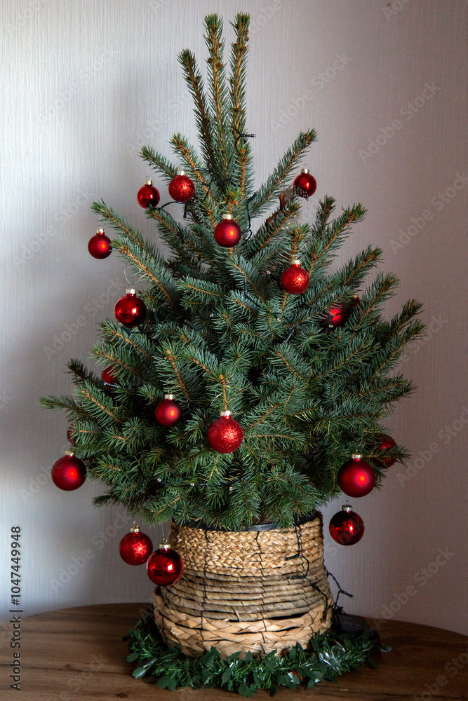 Artificial Christmas Tree with Red Decorations placed in a rustic straw ...