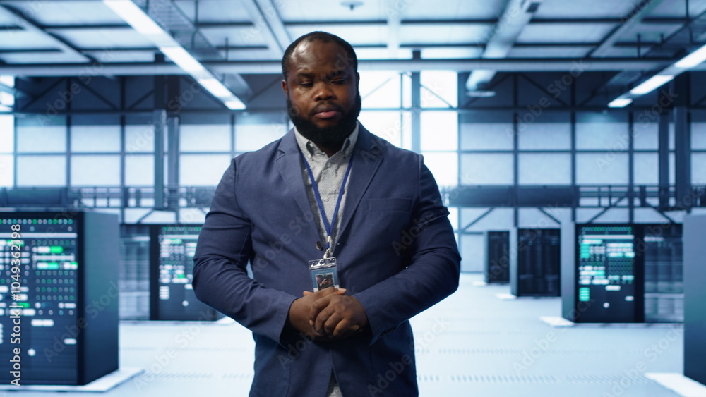 Technician walking between server rows in data center, doing yearly infrastructure inspection ...