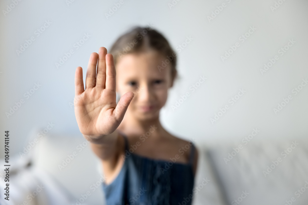 Little kid girl showing palm in focus from blurred background, making ...