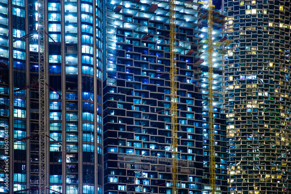 Bright lights illuminate the exteriors of towering skyscrapers in a ...