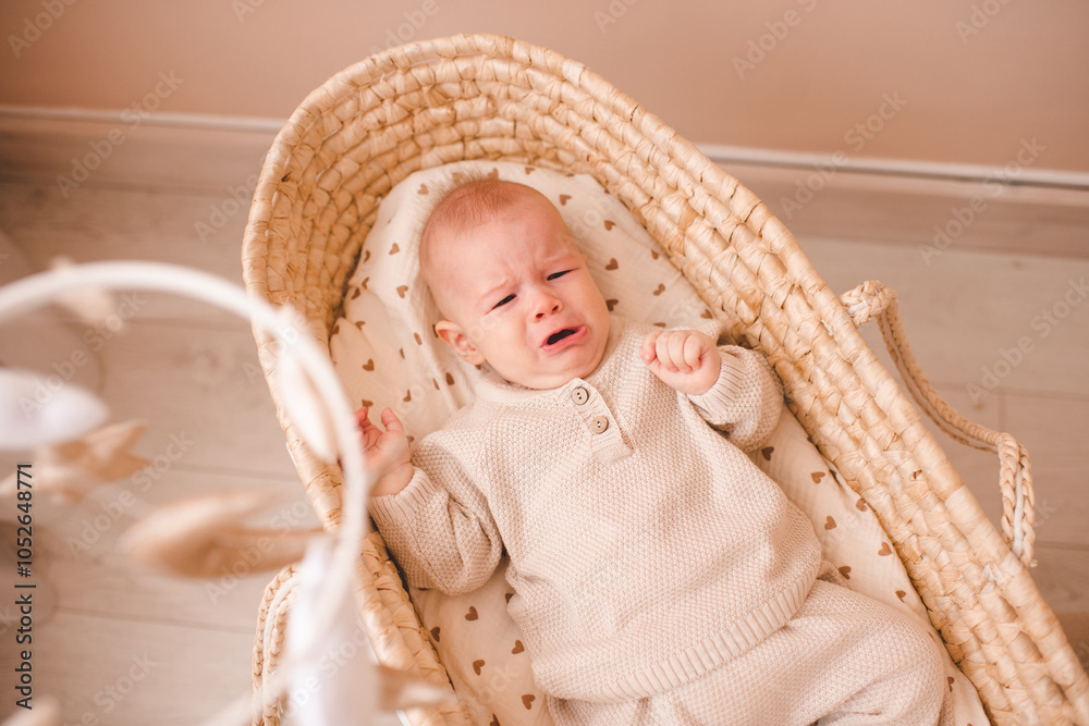 Crying baby boy lying in cradle with colic pain top view. Childhood ...