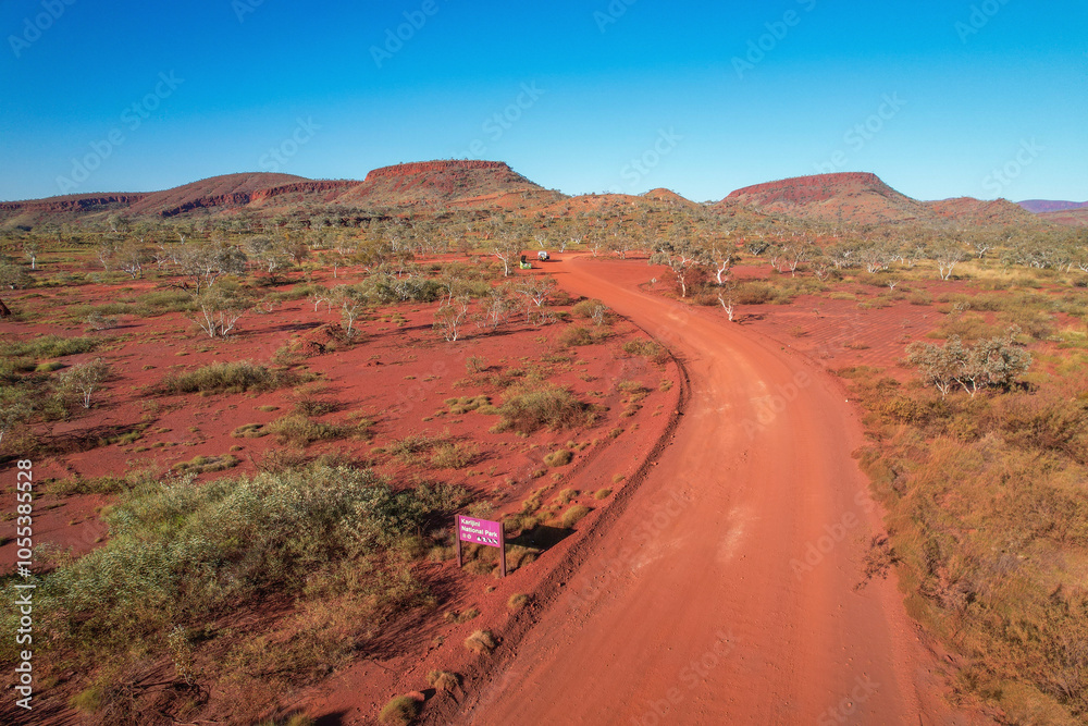 Aerial view of the scenic red earth landscape with a dirt road and rugged mountains, Nanutarra ...