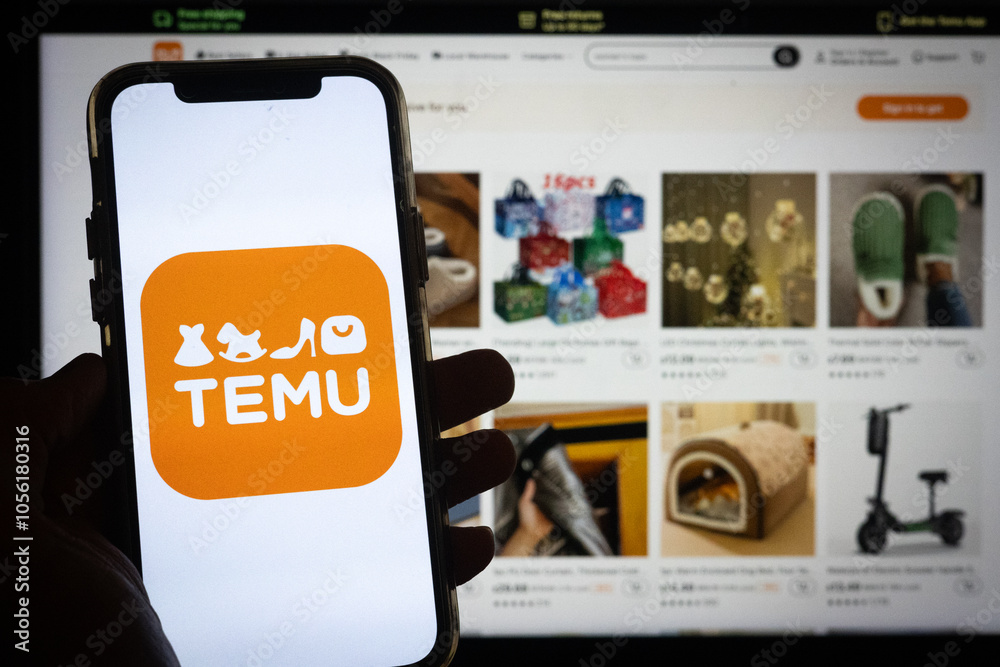 Silhouette of Hand Holding Phone with Temu Logo in Front of Temu Online ...