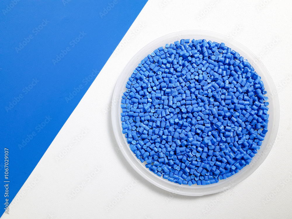 Blue masterbatch granules in a cup on a blue and white background, a ...