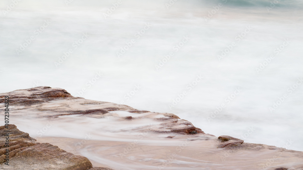 Slow shutter speed photo of ocean water flowing over a rock, located at ...