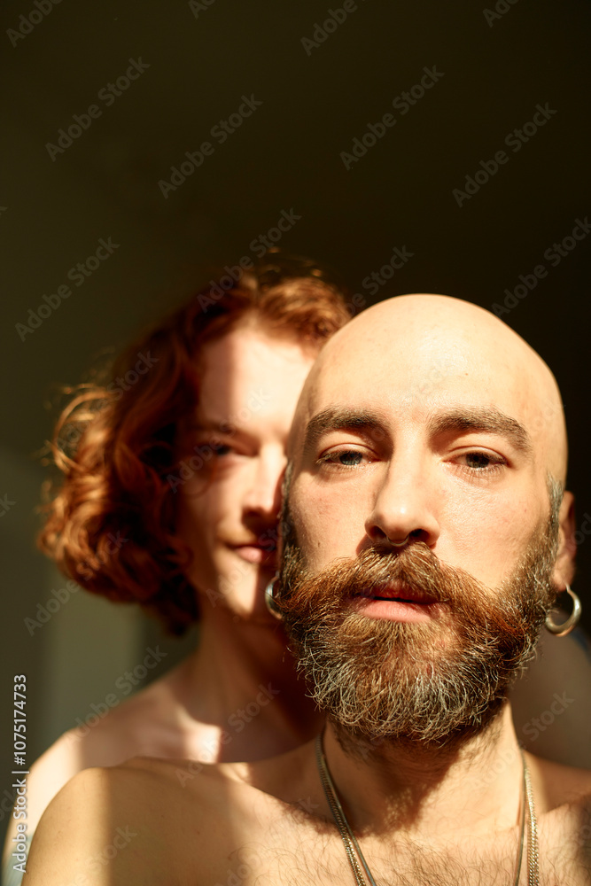 Sunlight highlights the faces of a bearded man and his partner in the ...