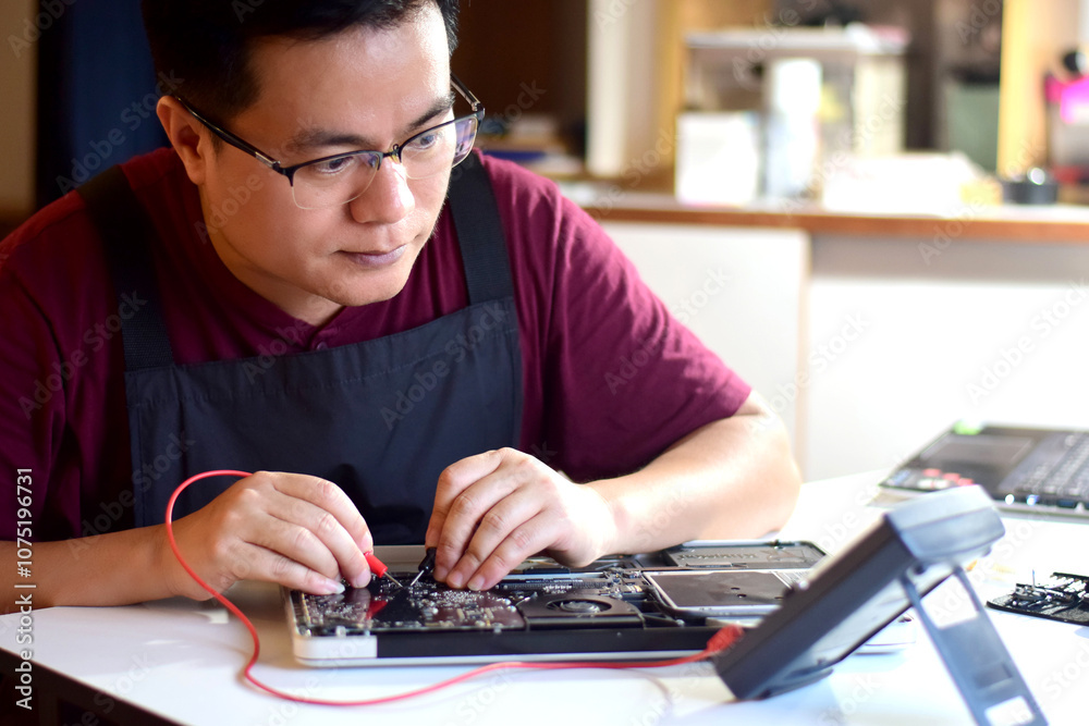 Computer technician wearing glasses A laptop motherboard repairman is ...