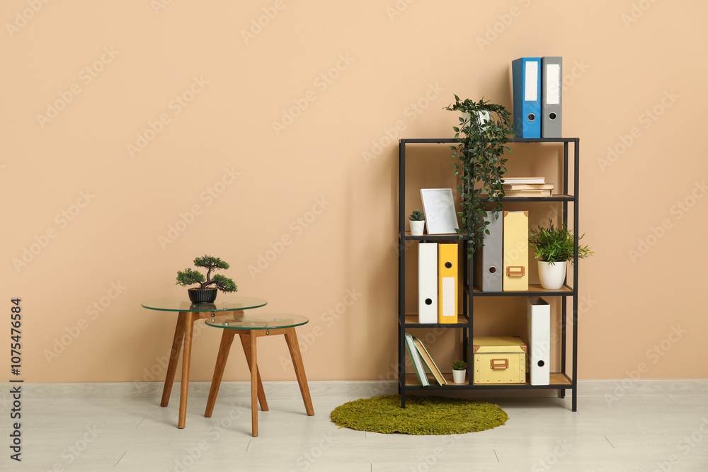 Shelf unit with document folders, plants and tables near beige wall in ...