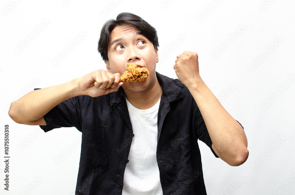 Asian Man eating and Biting Crispy Fried Chicken Thigh with a Look of ...