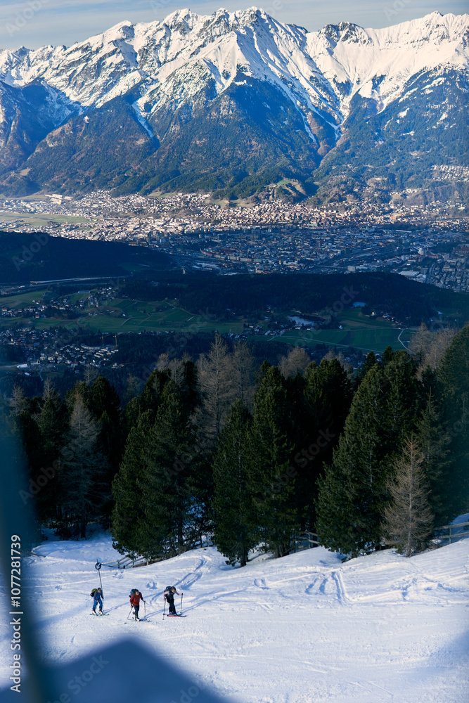 Skiers descend a snowy mountain trail with breathtaking views of the ...