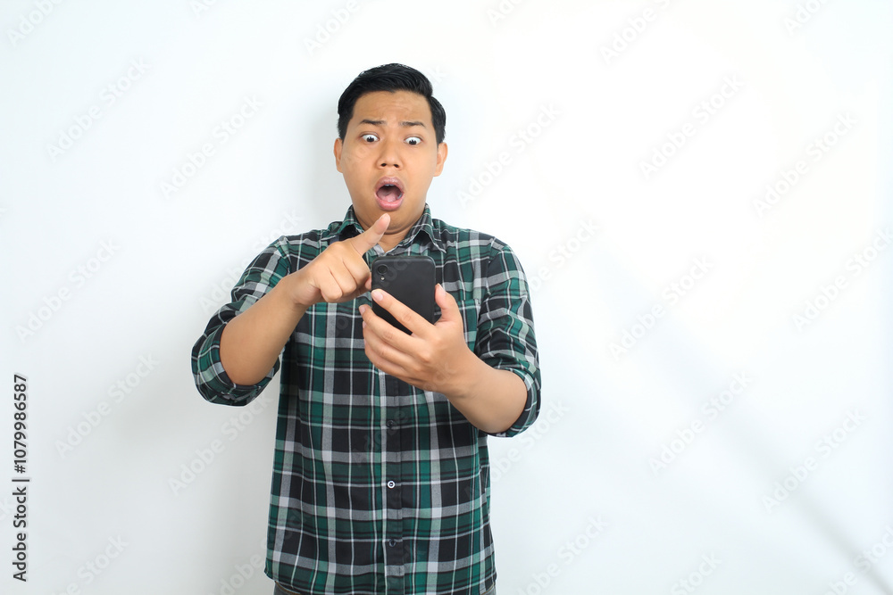 asian man looks shocked while scrolling social media on smartphone isolated on white background ...