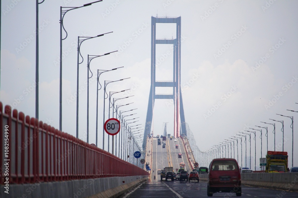 A long bridge stretches across, lined with street lights and vehicles ...