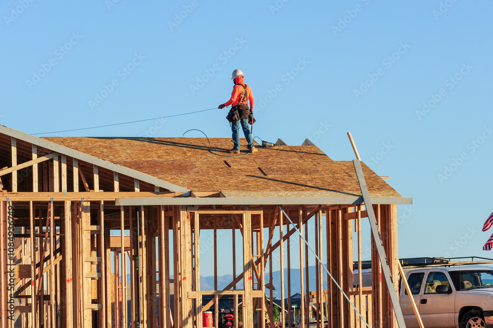 A construction worker atop the structure of a home under construction ...