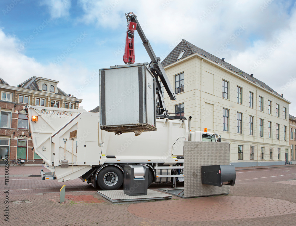 Garbage truck with crane, lifting a underground waste container in the ...