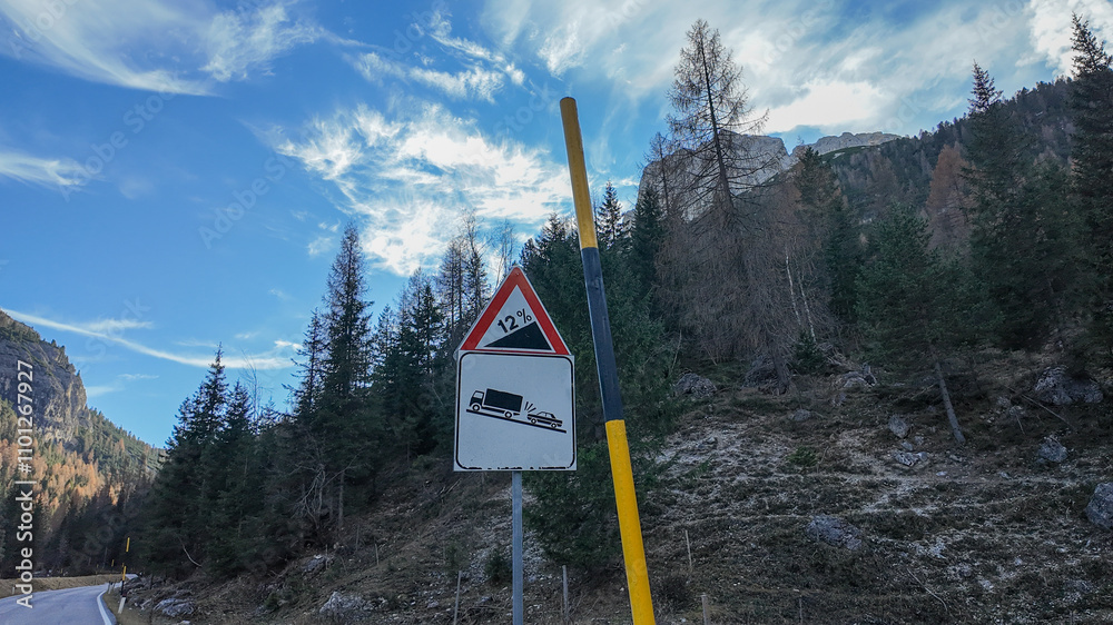Mountain road with a steep 12% descent warning sign amidst dense ...