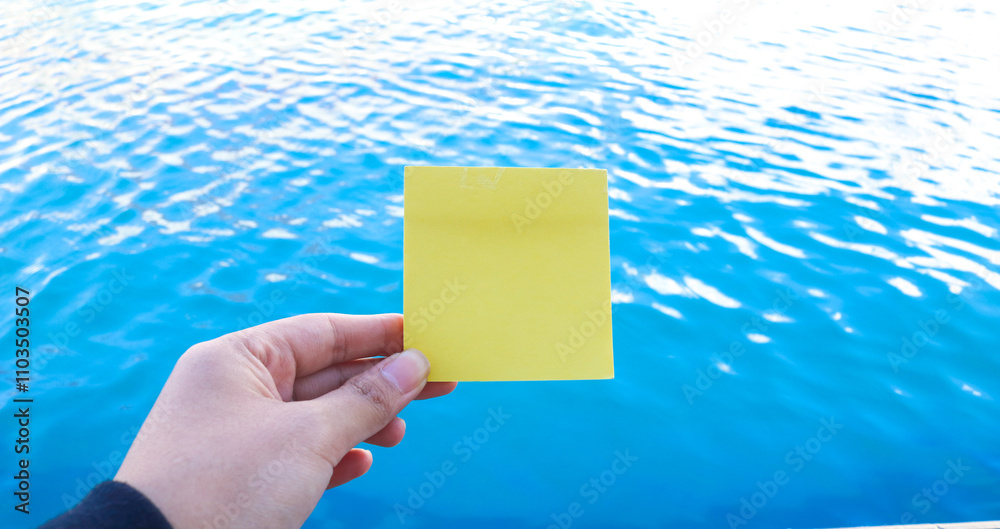Hand holding blank yellow sticky note paper with swimming pool and blue ...