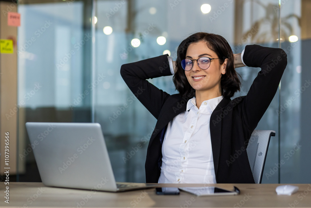 Businesswoman in office confidently relaxes at desk with laptop and ...