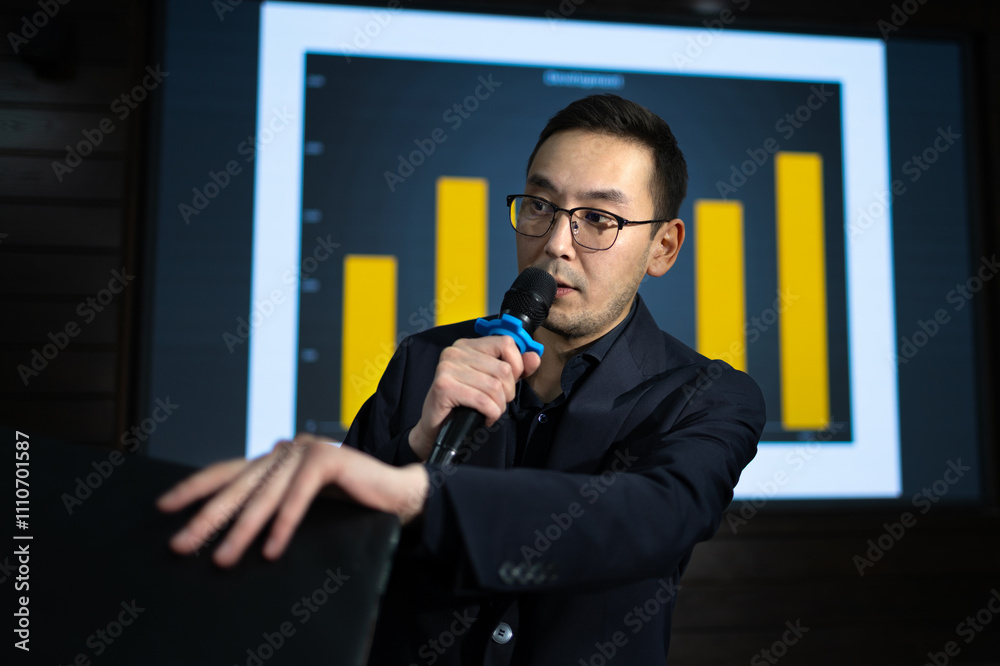 Male person in glasses and dark costume delivers presentation on ...