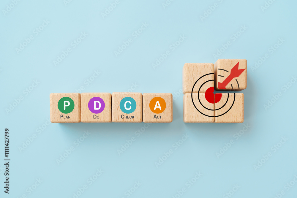 PDCA text on wooden cube blocks with dartboard icon on blue background ...