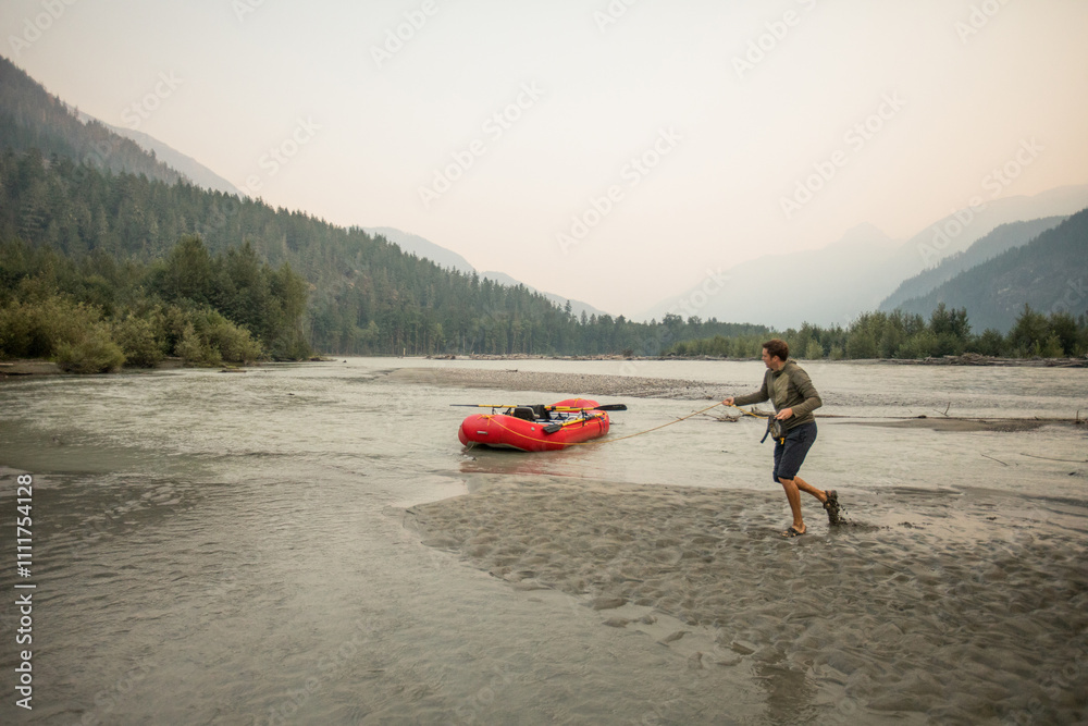 Raft guide walks his raft down to his campsite on the Squamish River ...