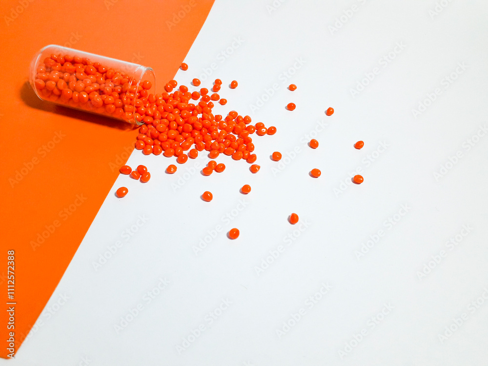 Orange masterbatch granules with glass tube on white and orange ...