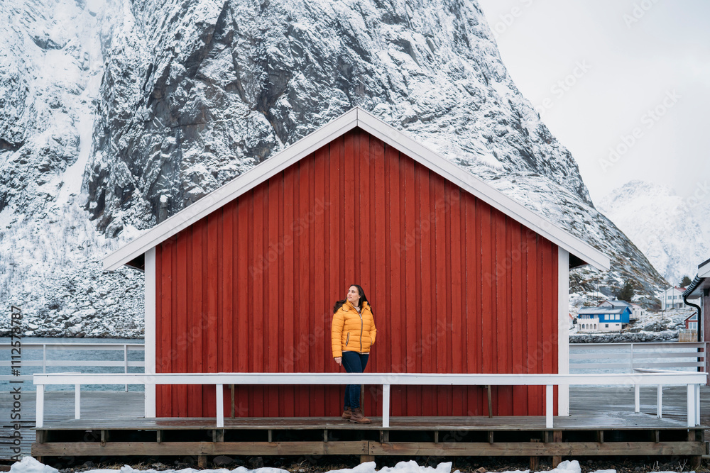 Tourist enjoying winter landscape at red wooden cabin in lofoten ...
