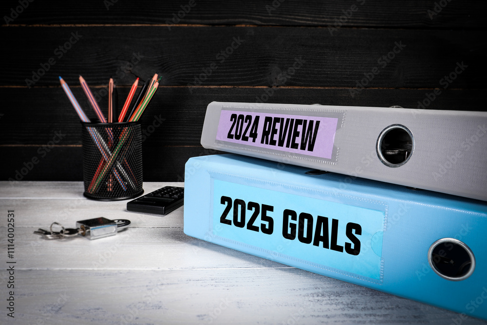 2024 Review and 2025 Goals. Two binders on desk in the office. Business ...