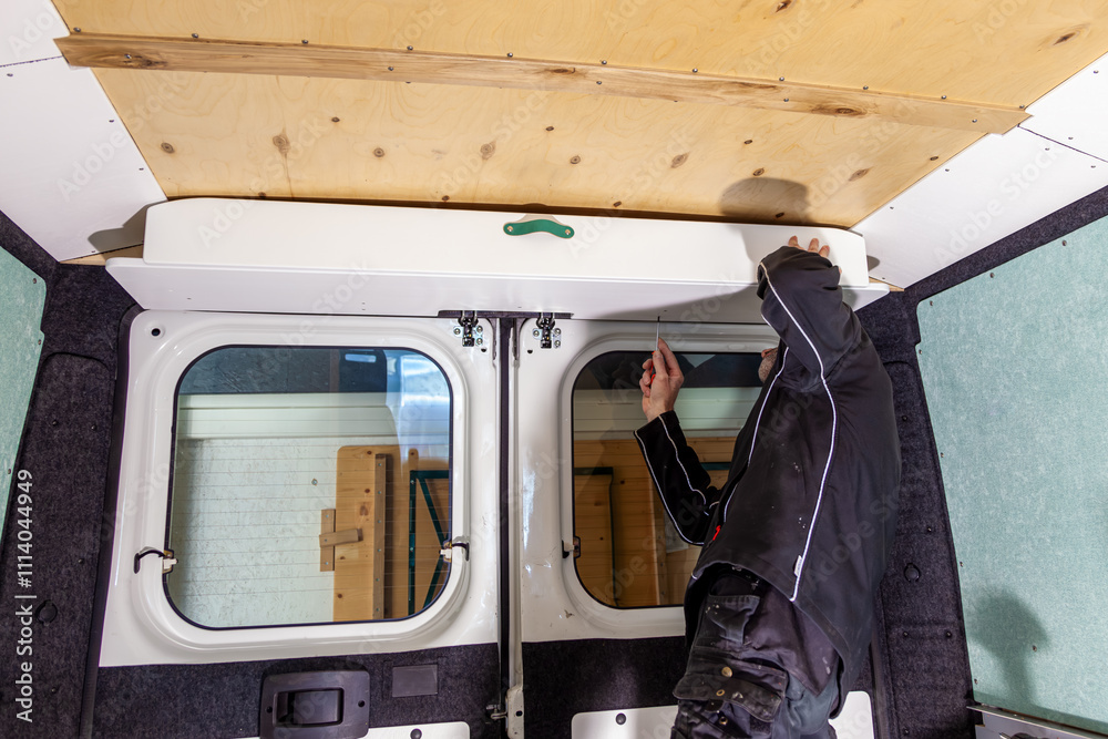 Camper van conversion. joiner working on a shelf. mounting a cupboard ...