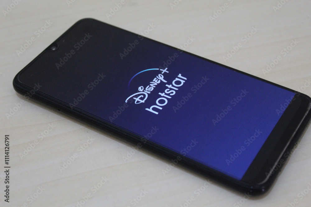 Disney+ Hotstar app logo display on a smartphone, black background hold ...