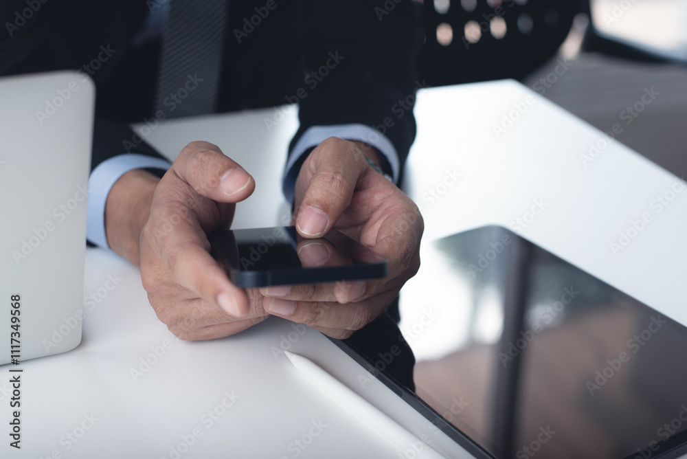 Businessman in black suit using mobile phone during working at office ...