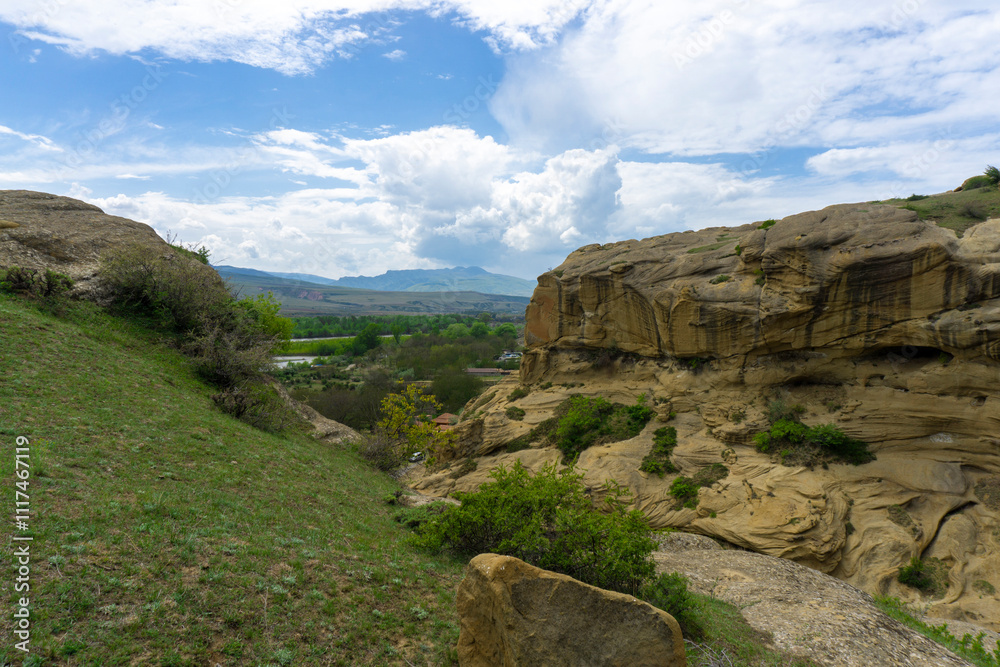 Gorge between green grass field and sandstone cliffs. Mountains, hills ...